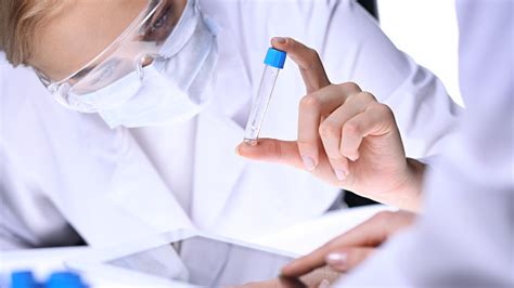 과학 연구 팀의 실험실에서 솔루션 선택을 취소 합니다 금발 여성 화학자 그녀의 동료 결과 태블릿 Pc 검사 하는 동안 유리의 테스트 튜브를 보유 하고있다 혈액 검사 약 또는