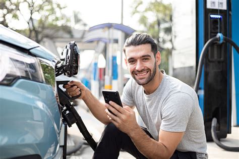 Pria Tampan Memegang Konektor Pengisian Dc Ccs Tipe 2 Ev Di Stasiun Pengisian Ev Dengan Mobilnya