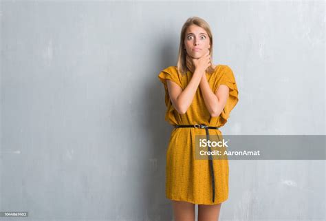 아름 다운 젊은 여 서 그런 지 회색 드레스 소리를 입고 벽과 질 식 때문에 고통 스러운 목을 건강 문제입니다 질 식 자살 개념 건강관리와 의술에 대한 스톡 사진 및 기타