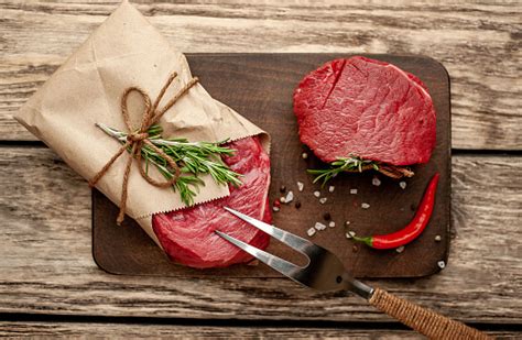 정육점에서 고기 2 장 종이에 싸서 고기 한 조각 재료와 어두운 콘크리트 배경에 스테이크의 형태로 쇠고기의 조각 고기에 대한