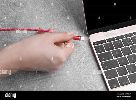 Woman Plugging USB Cable With Type C Connector Into Laptop Port At Grey Table Closeup Stock