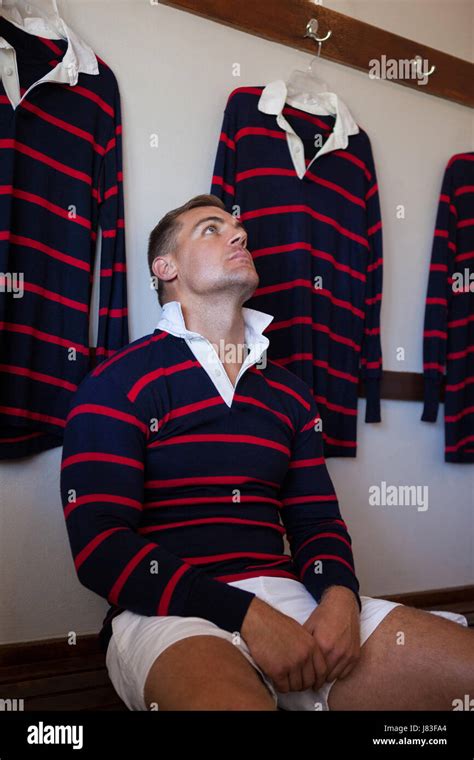 Tired Rugby Player Looking Up While Sitting On Bench At Locker Room