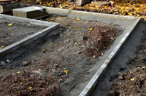 포장 구조 기초에 콘크리트 연석을 누워 건설 작업 굴삭기 빌더는 새로운 거리 표면을 만들고있다 타일은 자갈에 놓입니다 가을 작업 공간 스쿱 바퀴 0명에 대한 스톡 사진 및