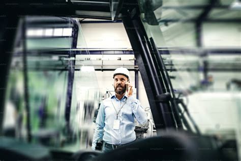 공장에서 스마트폰을 들고 전화를 거는 성숙한 산업가 엔지니어의 초상화 사진 Unsplash의 사업 이미지