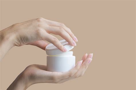 여성의 손은 흰색 화장품 패키지의 모형을 엽니 다 베이지 색 배경에 바디 크림의 둥근 항아리를 두 손 뷰티 산업의 개념 메이크업 화장품에 대한 스톡 사진 및 기타 이미지