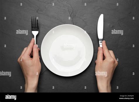 Woman With Empty Plate And Cutlery At Black Table Top View Stock Photo Alamy