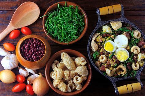 Feijao Tropeiro는 소박한 나무 테이블에 콩 베이컨 소시지 콜라드 그린 계란으로 만든 브라질 요리의 전형적인 요리입니다 콩 콩과에 대한 스톡 사진 및 기타 이미지