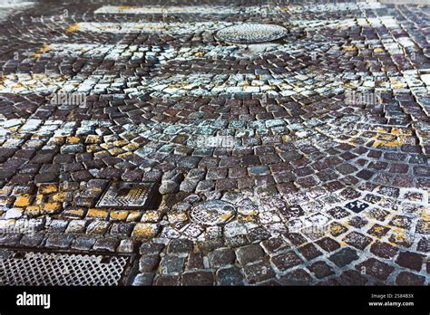Cobblestone Street With A Circular Pattern Manhole Covers And Drainage Grates Cobblestones Are