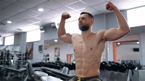 The Bodybuilder Tenses His Muscles Looks Straight Ahead Without A
