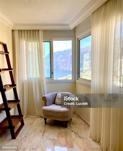 바다 전망과 절벽 전망을 감상할 수 있는 쾌적한 침실 인테리어 긴 커튼 대리석 바닥 편안한 안락의자가 있는 밝고 쾌적한 디자인 발코니에 대한 스톡 사진 및 기타 이미지