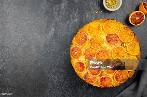 어두운 돌 배경에 피스타치오 너트와 피스타치오 너트와 함께 피 오렌지와 폴렌타 케이크를 거꾸로 감귤류와 함께 만든 케이크 맨 위 보기입니다 공간을 복사합니다 거꾸로에 대한