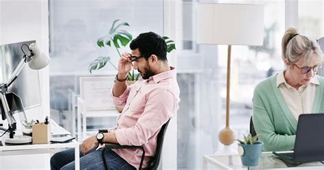 남자 피곤하고 사무실에서 바쁜 일정과 마감 시간을 위해 안경을 쓴 사무실에 컴퓨터가 있는 책상 동료 스트레스와 목표와의 초과 근무에 대한 프로젝트 또는 작업의 피로로