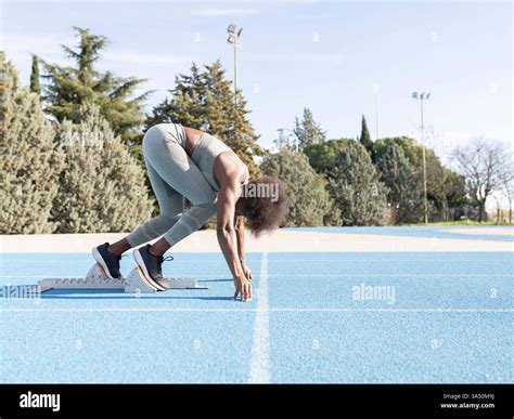 Black Woman On Starting Blocks In Crouch Position Getting Ready For Sprint At Stadium Stock