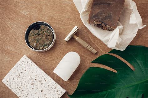 제로 웨이스트 플랫 레이 천연 비누 금속 주석의 고체 샴푸 재사용 가능한 면도기 크리스탈 에코 데오도란트 녹색 몬스테라 잎이 있는 나무 배경의 스폰지 플라스틱