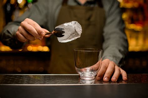 남성 바텐더의 손은 투명한 유리 위에 얼음 조각이 있는 강철 집게를 들고 있습니다 각얼음에 대한 스톡 사진 및 기타 이미지 각얼음 강철 결정체 Istock