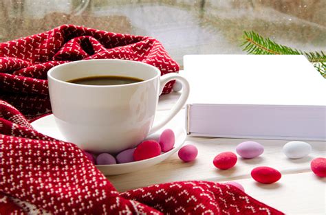 따뜻한 스카프와 흰색 책 옆에 있는 나무 창틀에 여러 가지 색의 과자를 곁들인 흰색 커피 한 잔 0명에 대한 스톡 사진 및 기타