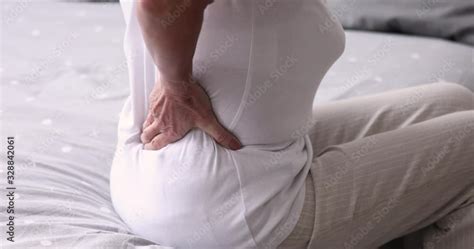 Senior Grandma Massaging Back Muscles Sitting On Bed Old Woman Touching Spine Feeling Backache