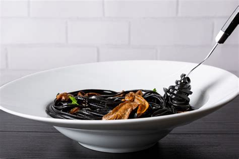 밀 싹 및 검은 오징어 잉크와 함께 파스타입니다 버섯 소스입니다 향미료와 올리브 오일입니다 프레임에서 액션입니다 스파게티는 포크의 주위에 싸여 있다 공간에 복사 합니다 0