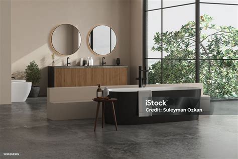 베이지 색 벽이있는 현대적인 욕실 인테리어 이중 거울이있는 대리석 분지 검은 욕조 및 회색 콘크리트 바닥 현대적인 가구가있는 미니멀리스트 욕실 나무와 가로 보기가 내려다 보