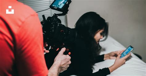 전문 카메라를 들고 있는 남자 근처 침대에 누워 스마트폰을 들고 있는 여자 사진 Unsplash의 무료 여배우 이미지