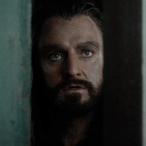 A Man With Long Hair And Blue Eyes Looking Out From Behind A Door