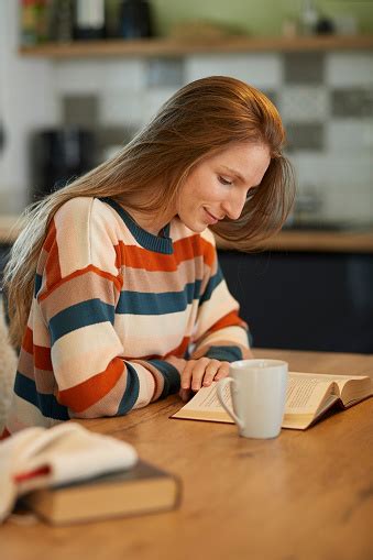 테이블에 앉아 아름 다운 금발 여자 책 웃 고 크로 셰 뜨개질 기구 및 책을 읽고 테이블에 가정 주방에 대한 스톡 사진 및 기타 이미지 Istock