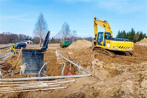 굴삭기는 건설 현장에서 참호를 파는다 외부 하수도 파이프를 놓는 트렌치 다층 건물을 위한 하수 배수 시스템 구덩이 기초를 파고 건설 산업에 대한 스톡 사진 및 기타 이미지