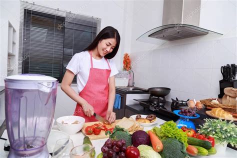 Mujer De Corte De Tomate A Bordo En La Sala De Cocina