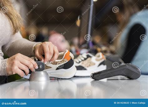 Empleado De La Tienda De Ropa Quitando La Alarma De Una Prenda De Vestir Foto De Archivo