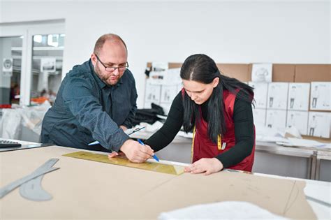 섬유 공장의 신제품 측정에 여성 디자이너와 함께 일하는 남성 포먼 2명에 대한 스톡 사진 및 기타 이미지 2명 가리키기