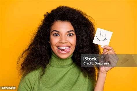 그녀의 이모티콘 고립 된 생생한 색상 배경과 함께 종이를 들고 혀를 들고 웃는 쾌활한 귀여운 예쁜 예쁜 긍정적 인 여자 친구의 사진을 닫습니다 갈색 머리에 대한 스톡 사진