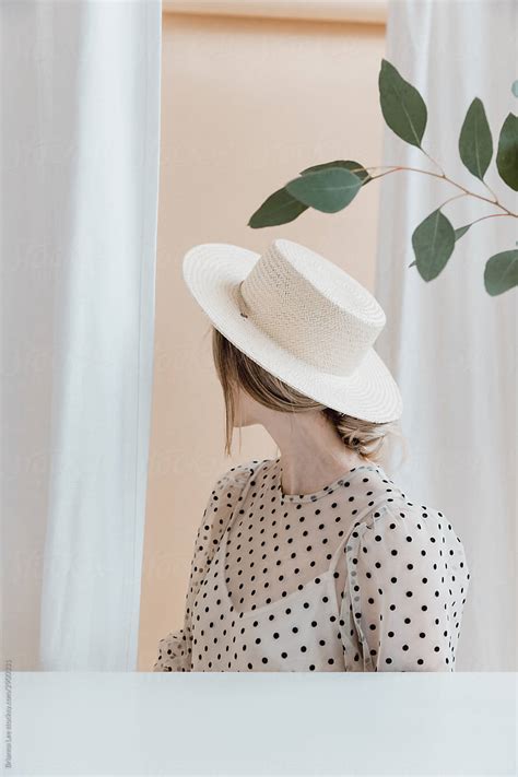 Girl In A Polka Dot Dress And Hat Sitting At White Table By Stocksy