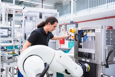 Premium Photo Man With Assembly Robot In Factory