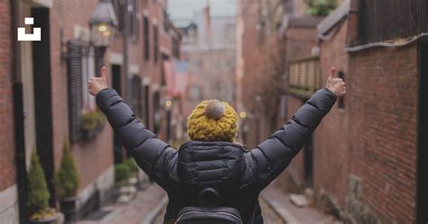 검은 가죽 재킷과 노란색 니트 모자를 쓴 사람이 낮에 보도를 걷고 있다 사진 Unsplash의 무료 미국 이미지