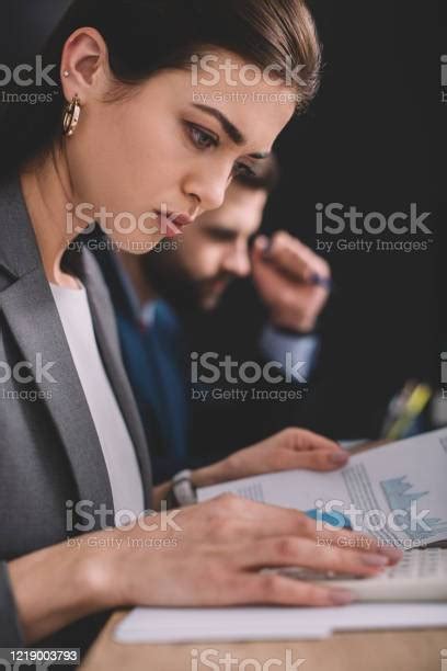 검정 색 배경에 동료 근처 종이에 계산기 및 차트와 함께 작업 하는 데이터 분석가의 선택적 초점 2명에 대한 스톡 사진 및 기타 이미지 Istock