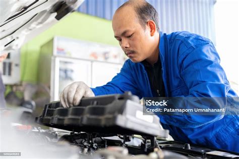 주기적인 엔진 점검은 차량의 수명을 연장합니다 기계 엔지니어는 드라이버를 사용하여 기계 덮개를 조립하여 차고의 수리점에서 너트를 단단히 문지릅니다 유지 보수 및 품질 관리