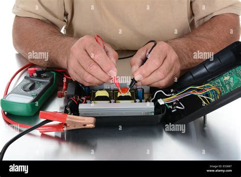 Closeup Of The Hands Of A Technician Testing Electrical Equipment On His Workbench Stock Photo