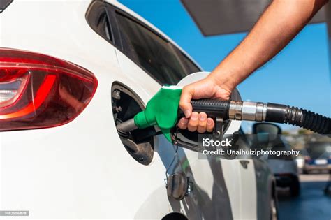 흰색 차에 휘발유나 디젤 연료를 연료를 보급하는 총을 든 남자의 손 교통 에너지 위기 석유 위기의 개념 가스 펌프의 가격 위기 속에서 가득 찬 탱크 펌프 정장용 구두에