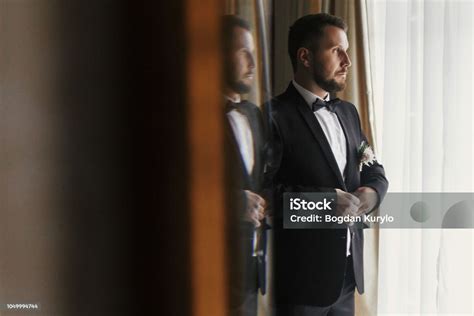 세련 된 신랑 양복과 창 빛에 나비 넥타이 씌우고 남자의 자신감과 행복 초상화입니다 아침에 준비 하 고 신랑 거울 반사와 크리에이 티브 웨딩 사진 턱시도에 대한 스톡 사진