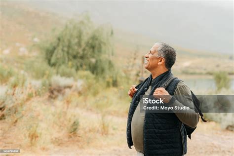 자연 건강 및 시골에서 하이킹을하고 배낭과 미소로 걷는 남자 행복하고 차분하고 은퇴 할 때 여행 모험을하는 선배 나무와 호수가있는 숲 풍경에서 트레킹 걷기에 대한 스톡 사진