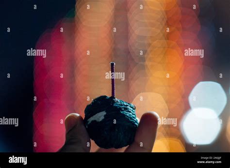 Human Hand Holding Green Sutli Rassi Bomb In Front Of Out Of Focus