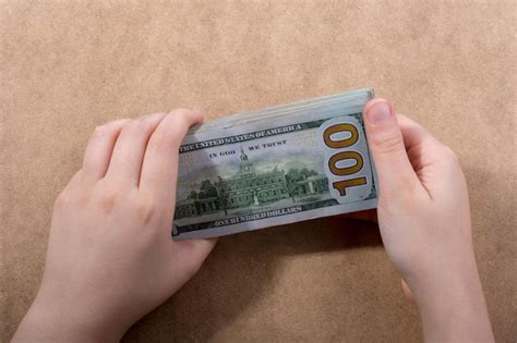 Premium Photo Midsection Of Person Holding Paper Currency On Table