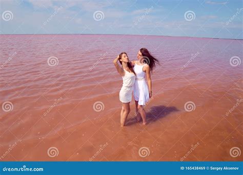 Two Hot Brunettes In A White Dresses Posing Near The Lake Stock Image