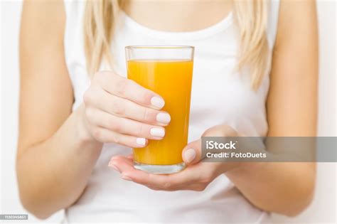 젊은 금발 여자 흰 셔츠에 오렌지 주스의 유리를 잡고 손입니다 맛 있는 건강 한 음료입니다 전면 보기 근접 촬영입니다 마시기에