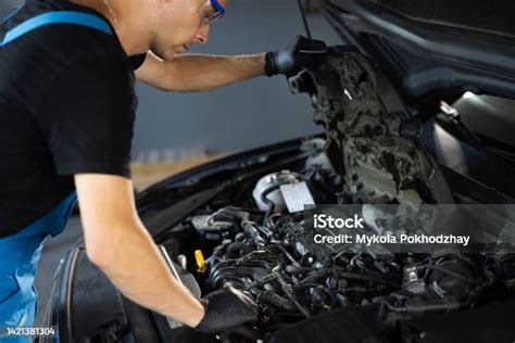 차고에서 열린 자동차 후드 엔진 수리 중 수리 부품을 주목하는 자동차 정비사 알아볼 수없는 정비사가 자동차 후드를 열고 엔진을