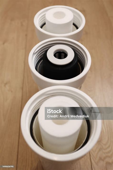 역삼투압 정수 시스템의 설치 또는 교체 나무 테이블 위에 3 개의 새로운 필터 카트리지가 들어있는 플라스틱 세트 집 물 여과 시스템 세계 물의 날 0명에 대한 스톡 사진 및
