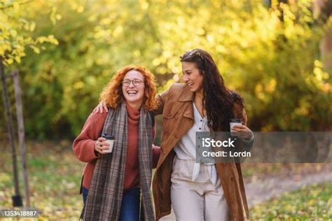젊은 쾌활한 여성 부부는 종이 컵에 커피와 함께 공원에서 걷고 좋은 시간을 보내고 우정에 대한 스톡 사진 및 기타 이미지 우정 공원 커피 마실 것 Istock