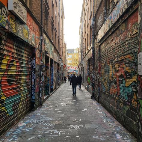 Narrow Alley Lined With Brick Buildings In A Graffiti Covered Urban