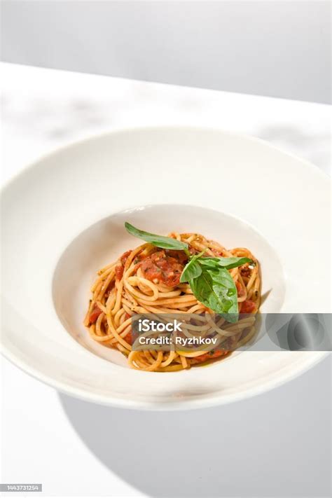 하얀 접시에 바질과 토마토를 곁들인 채식 파스타 여름 메뉴의 토마토 파스타 하드 섀도우 스파게티와 밝은 배경에 토마토 비건 음식 스파게티 마리나라 0명에 대한 스톡 사진 및