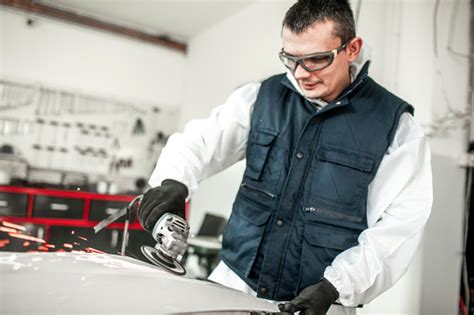 수리가 게에서 자동차 부품에 작업 하는 작은 전기 분쇄기를 사용 하 여 수리가 게 기술자 보호 장갑에 대한 스톡 사진 및 기타